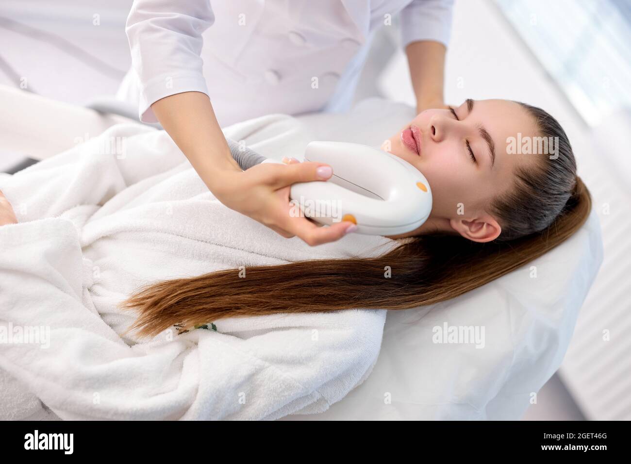 female lying in spa salon getting massage for face with professional ...