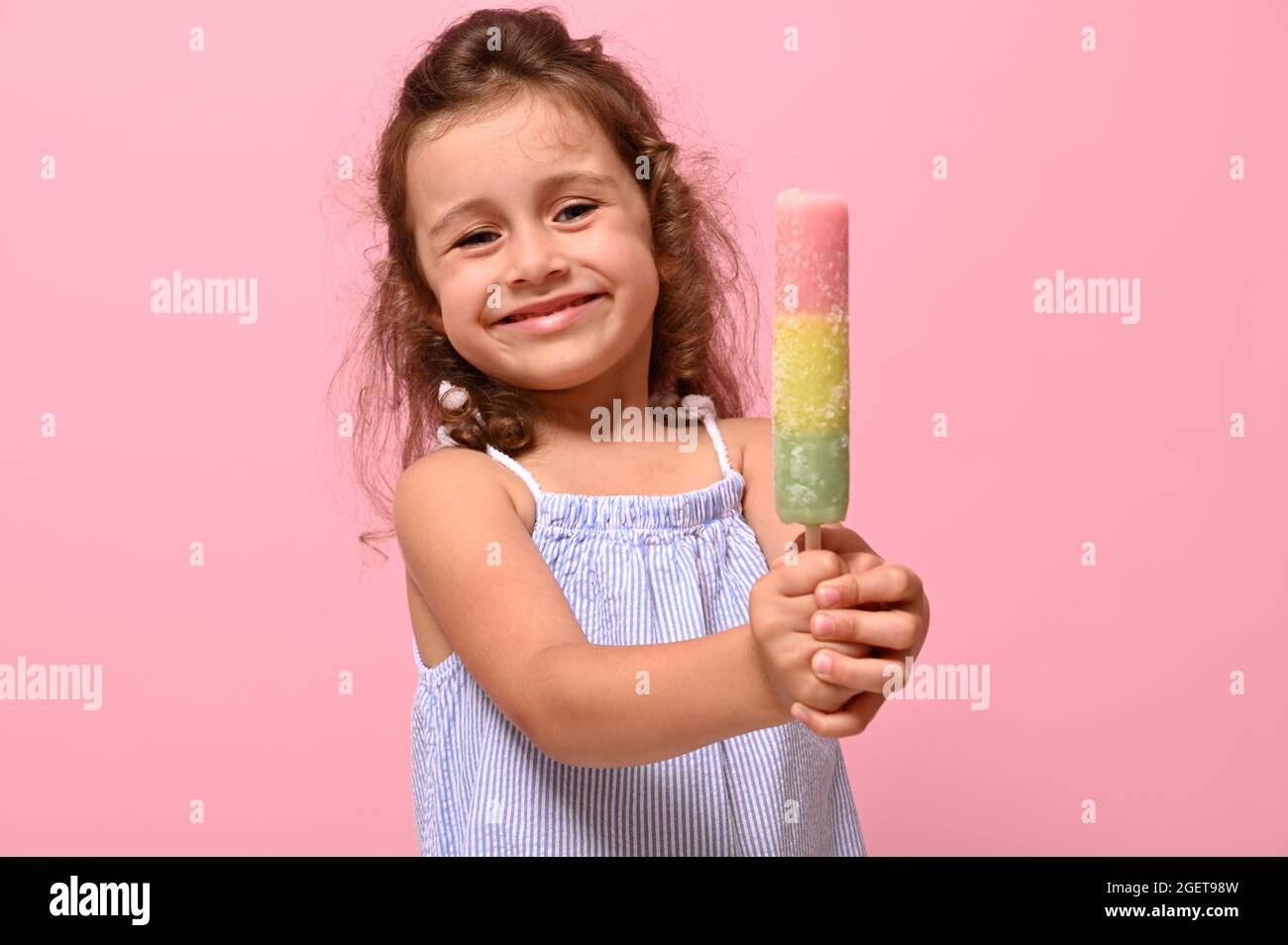 Funny cheerful little girl smiles showing to the camera a delicious ...