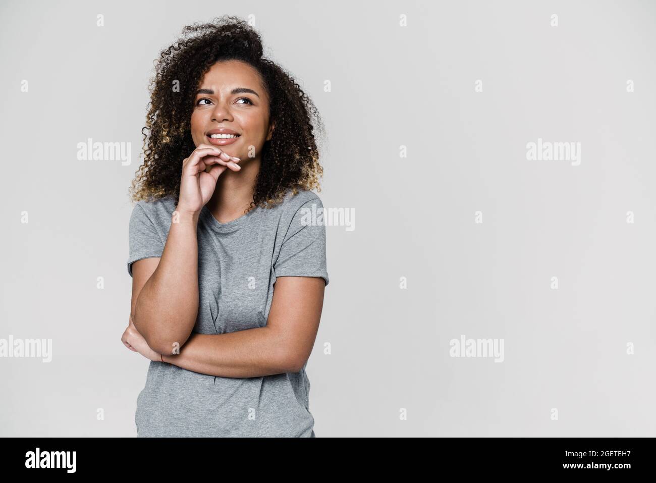 The smiling woman looking away with hand propping on the chin while ...