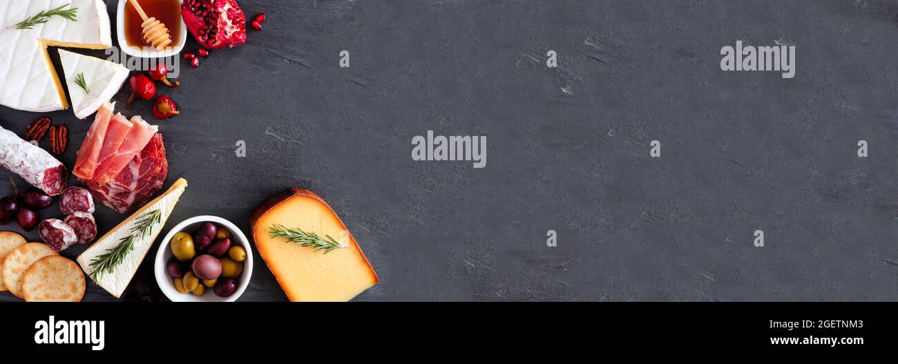 Variety of cheese and meat appetizers. Top view corner border on a dark ...