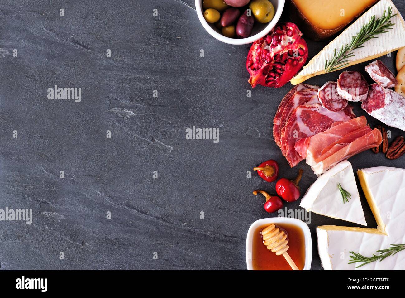 Assorted cheese and meat appetizers. Above view side border on a dark ...