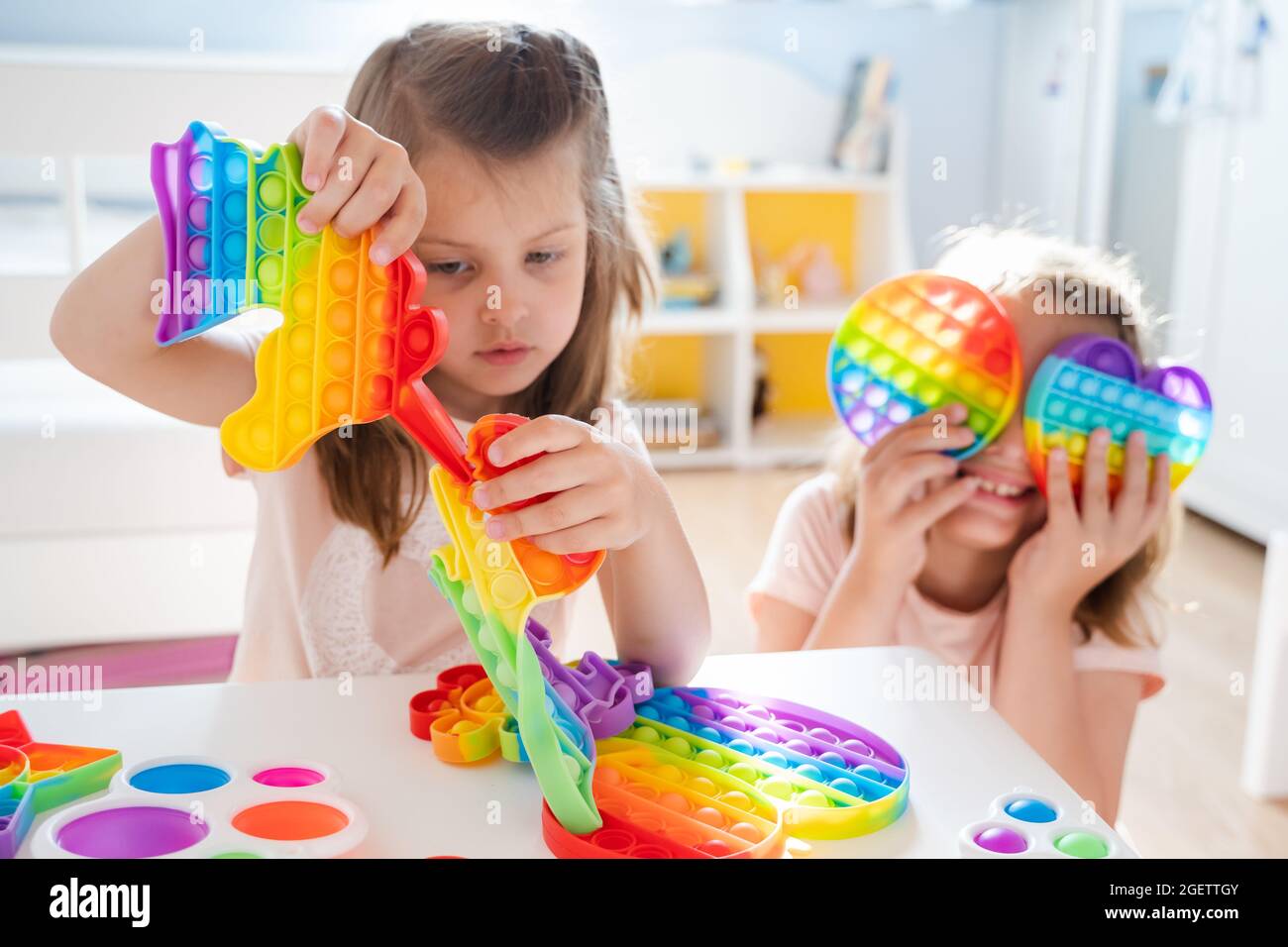 Little girls,kids,sisters play with colorful pop it children room ...
