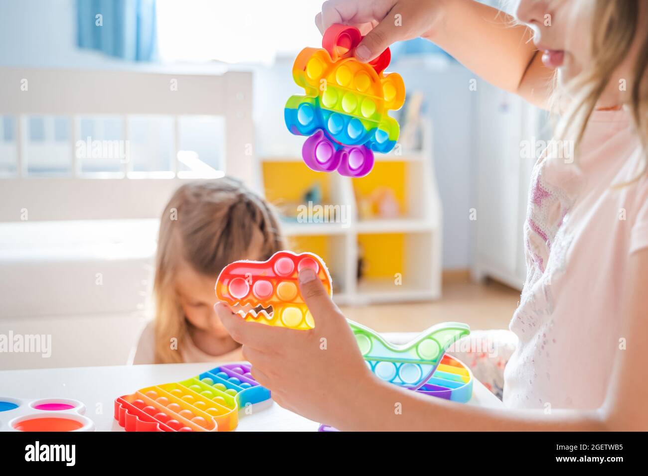 Little girls,kids,sisters play with colorful pop it children room ...