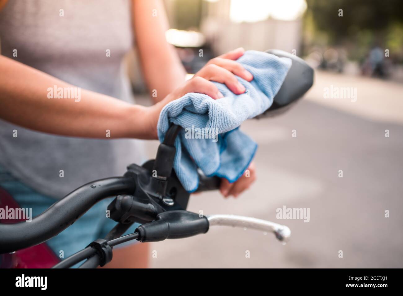Closeup of a person cleaning a modern motorcycle with a towel outdoors ...