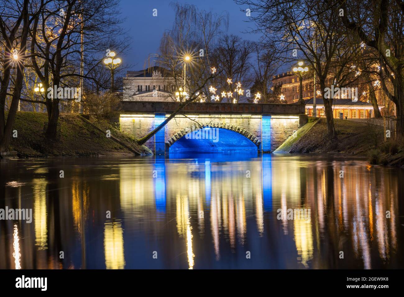 Riga canal with the bottom of the bridge illuminated in blue lights and ...