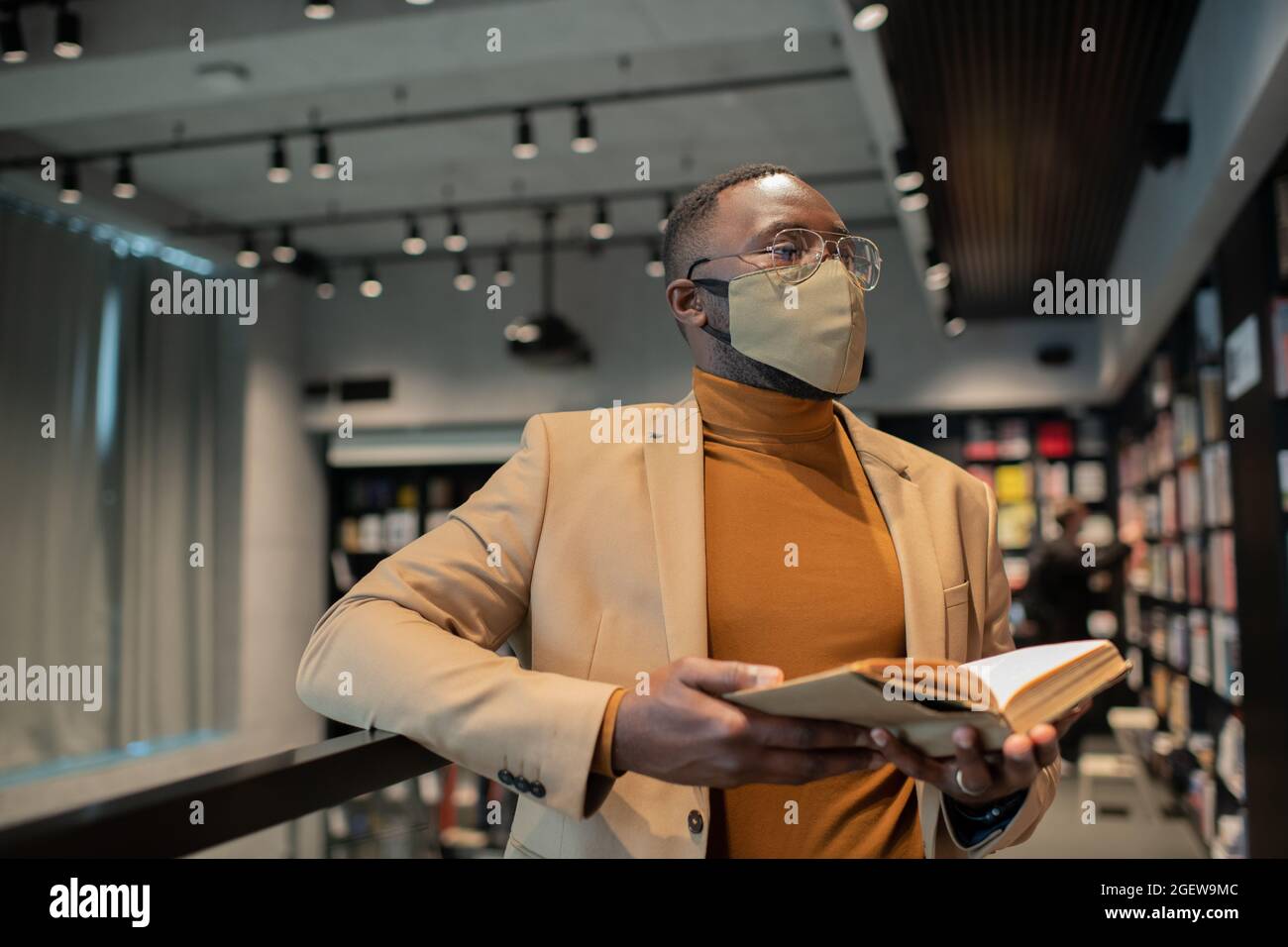 Young African man with open book looking at display with lots of ...