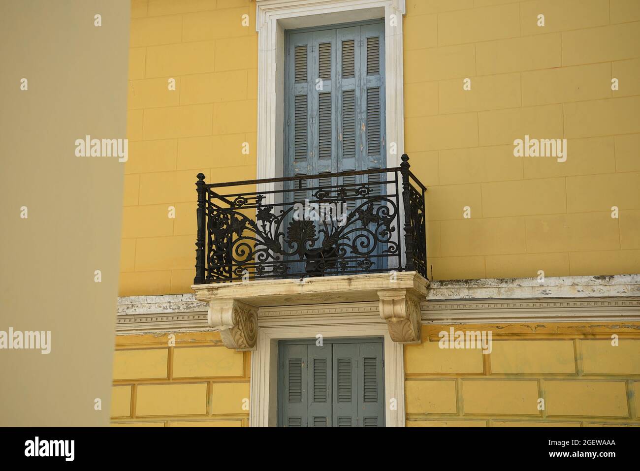 Neoclassical house facade with an ochre stucco wall, grey wooden window ...