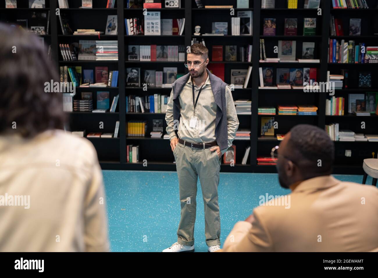 Strict young teacher or coach standing in front of intercultural ...