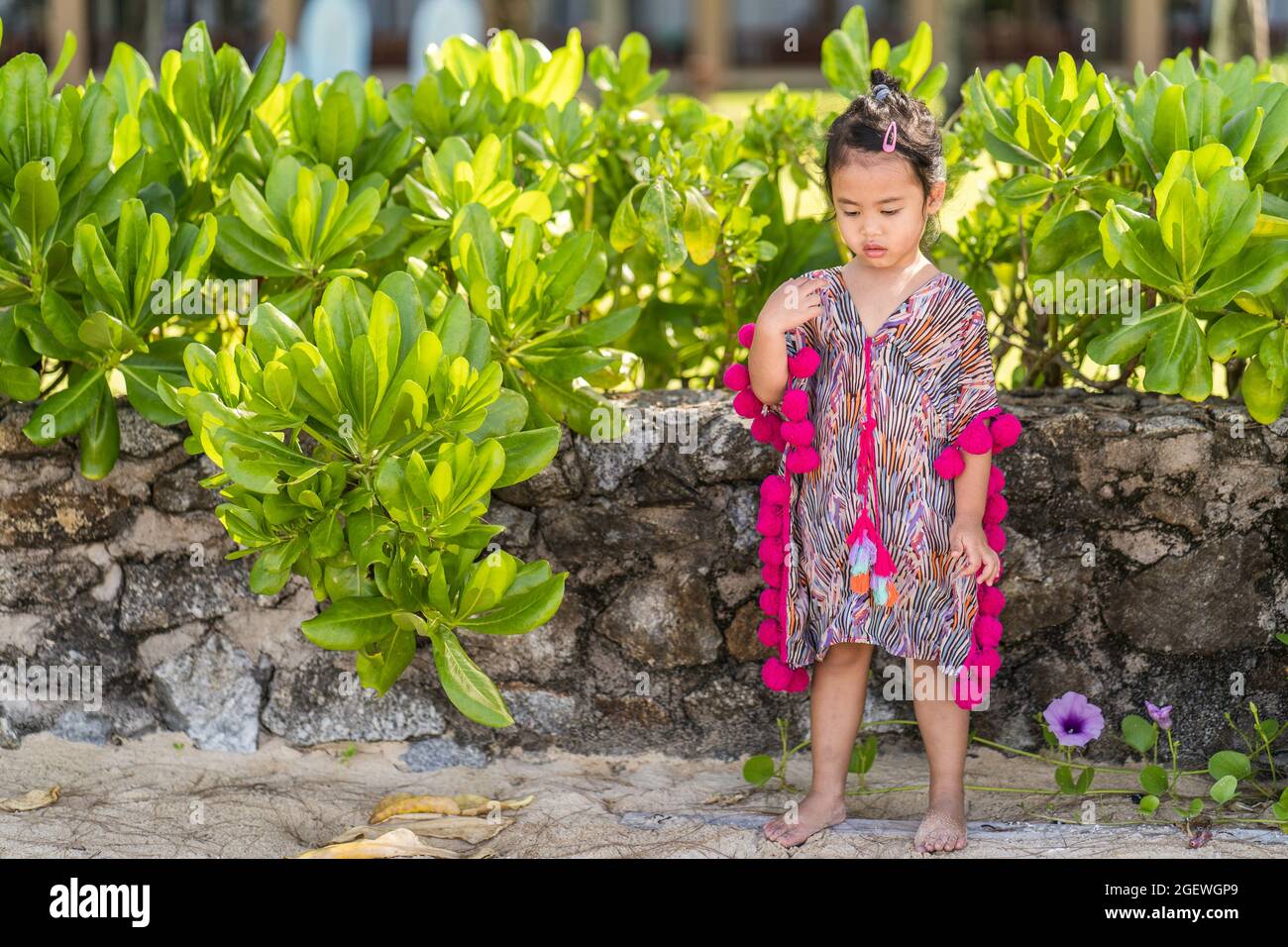 Cute little Thai girl in a traditional costume walking in a garden ...