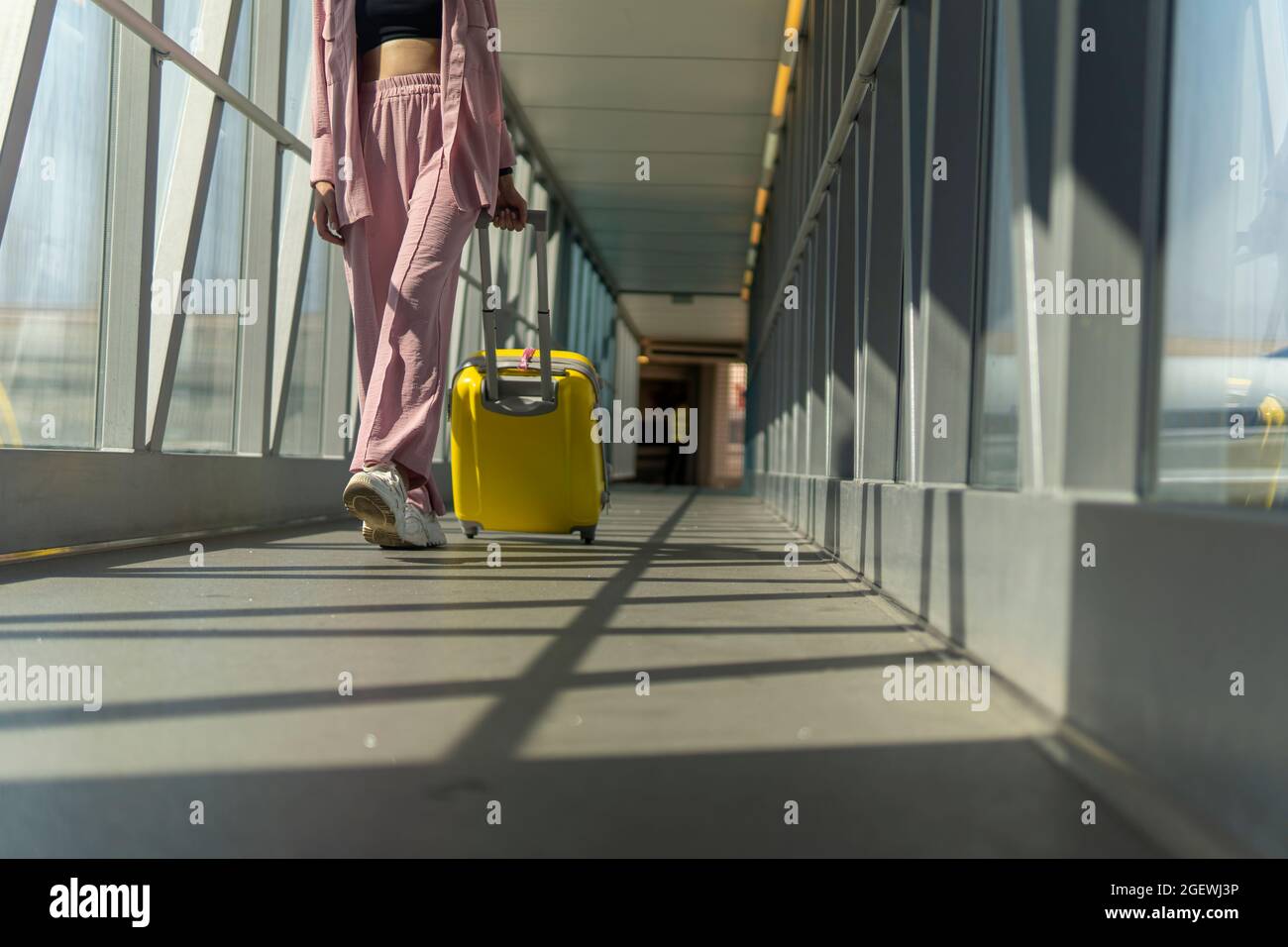 girl with a yellow suitcase walk through the terminal to the airport ...