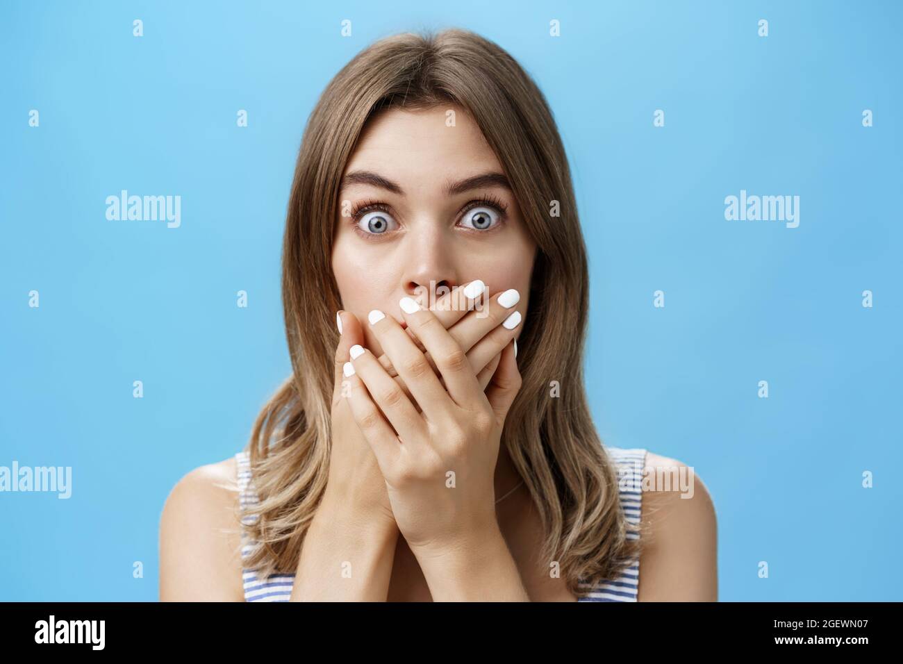 Close-up shot of shocked speechless woman covering mouth with pressed ...