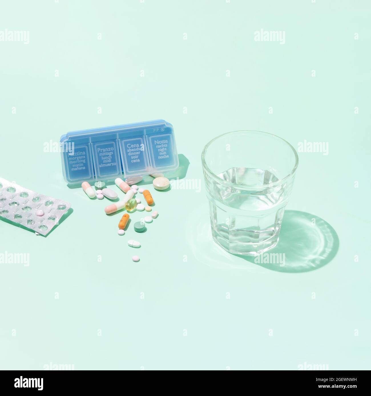 Medical drugs, tablets and pills with glass of waters on pastel green ...