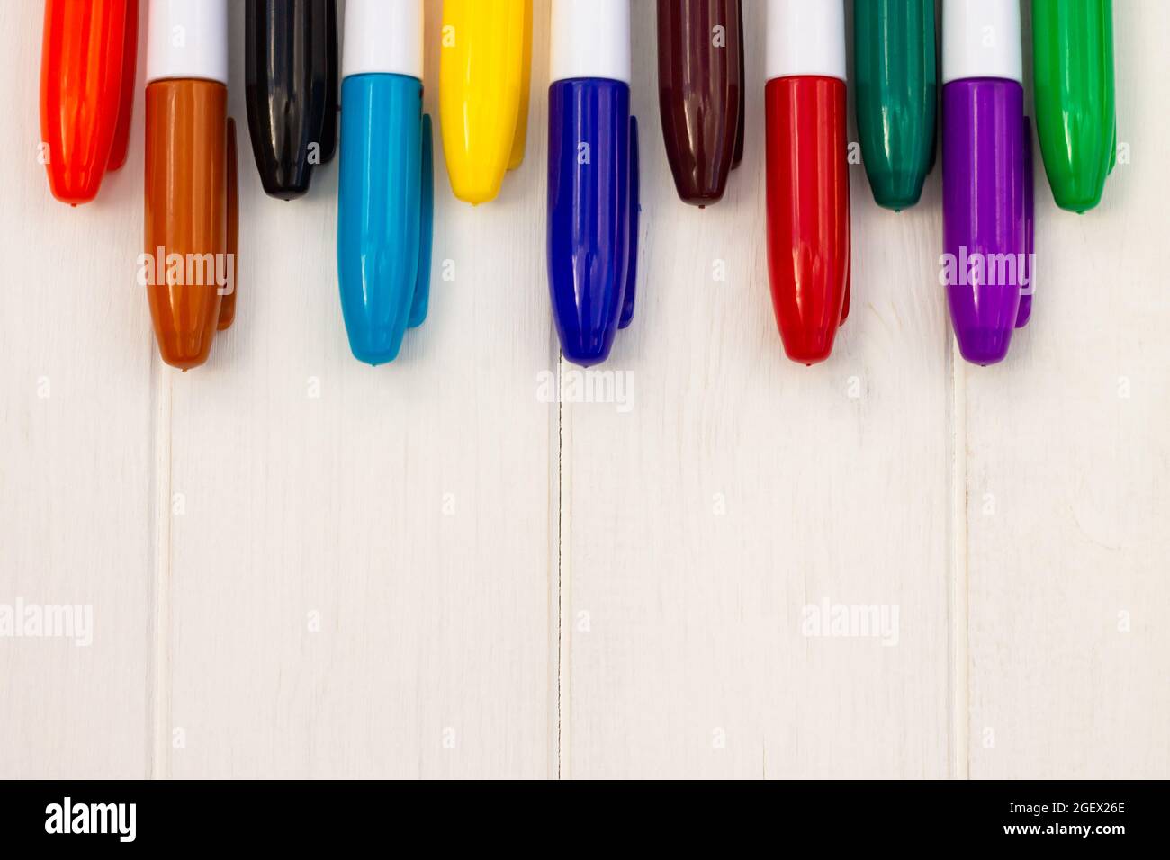 Multi-colored markers on a white wooden background. Top view. Copy ...