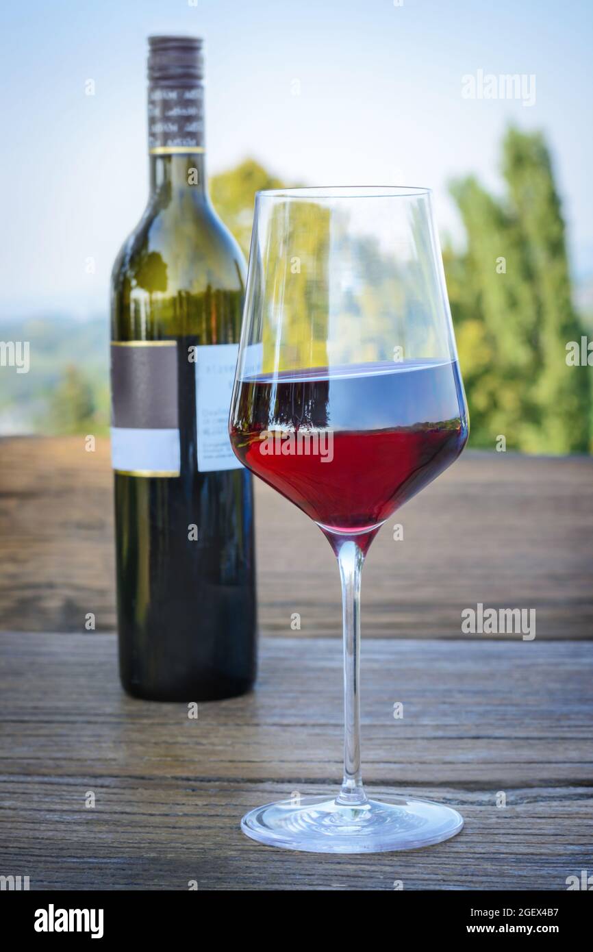 Glass of red wine on a street table on a blurred background, vertical ...