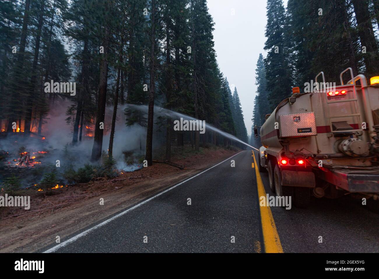 A water tender sprays water on a section of the Dixie Fire on Highway ...