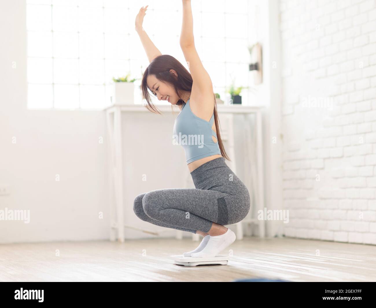 Excited woman sitting on scales at home, overjoyed with success of ...