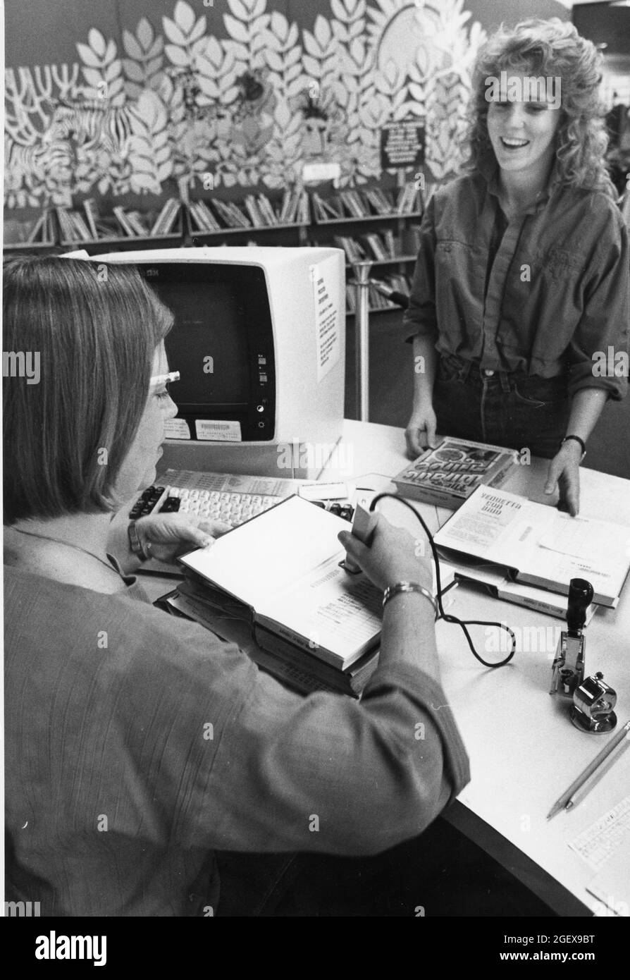 Austin Texas USA, circa 1988: Library clerk uses wand to scan barcode ...