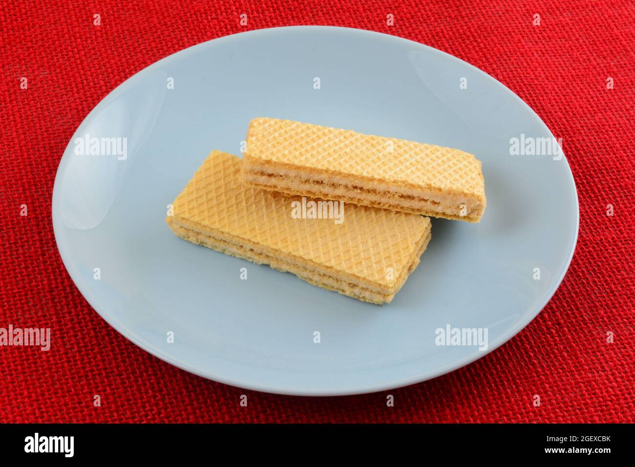 Two taro cream wafer cookies on blue snack plate on red background ...