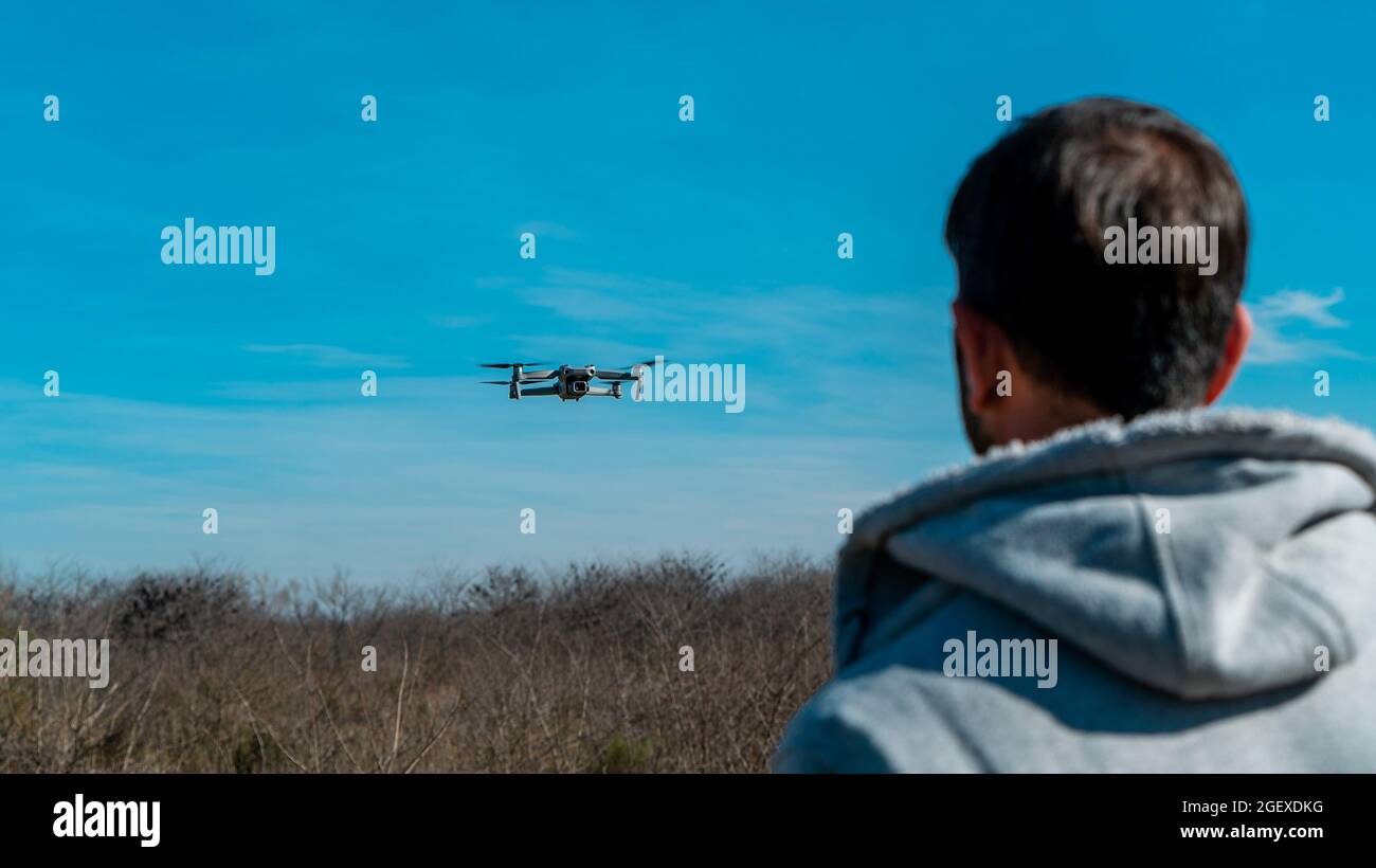 A back view of a guy flying a drone in the blue sky Stock Photo - Alamy