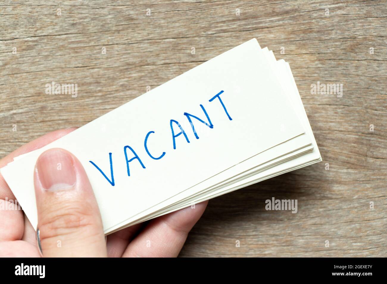 Man hold the flash card with handwriting word vacant on wood background ...