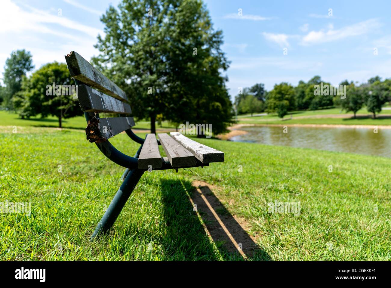 An old deteriorating wood and metal park bench in a grass field on a ...
