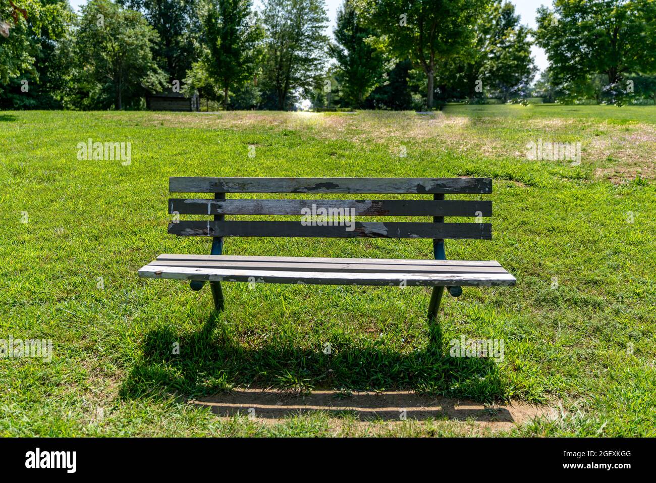 An old deteriorating wood and metal park bench in a grass field on a ...
