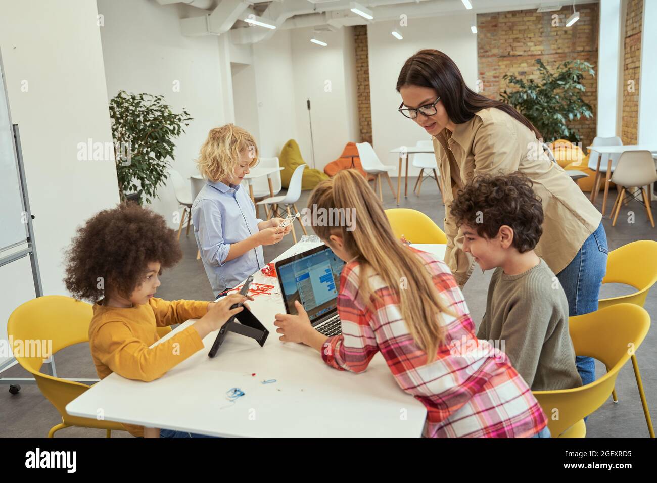 Fun and engaging. Happy children using gadgets during STEM class with ...