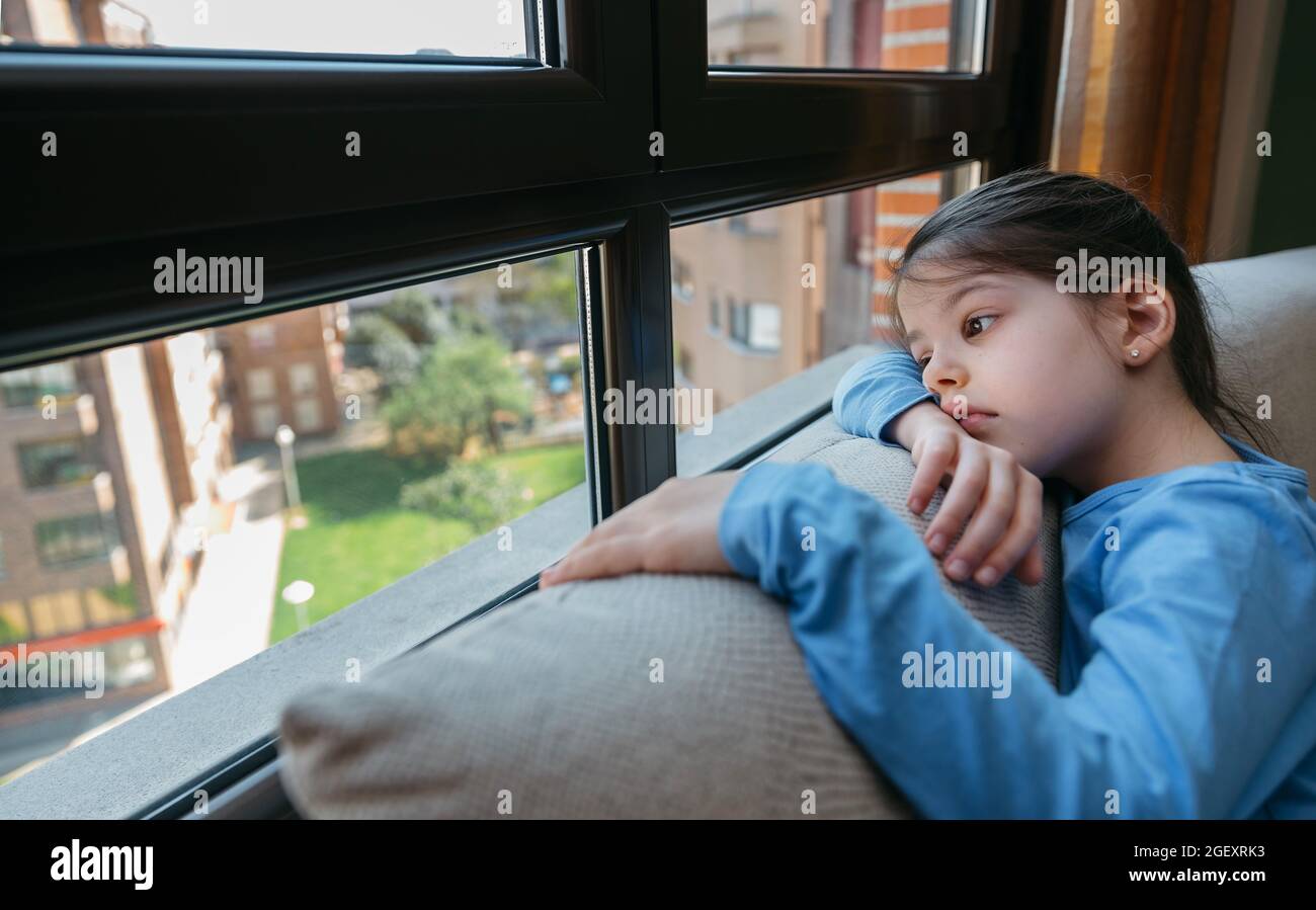 Sad girl looking out the window Stock Photo - Alamy