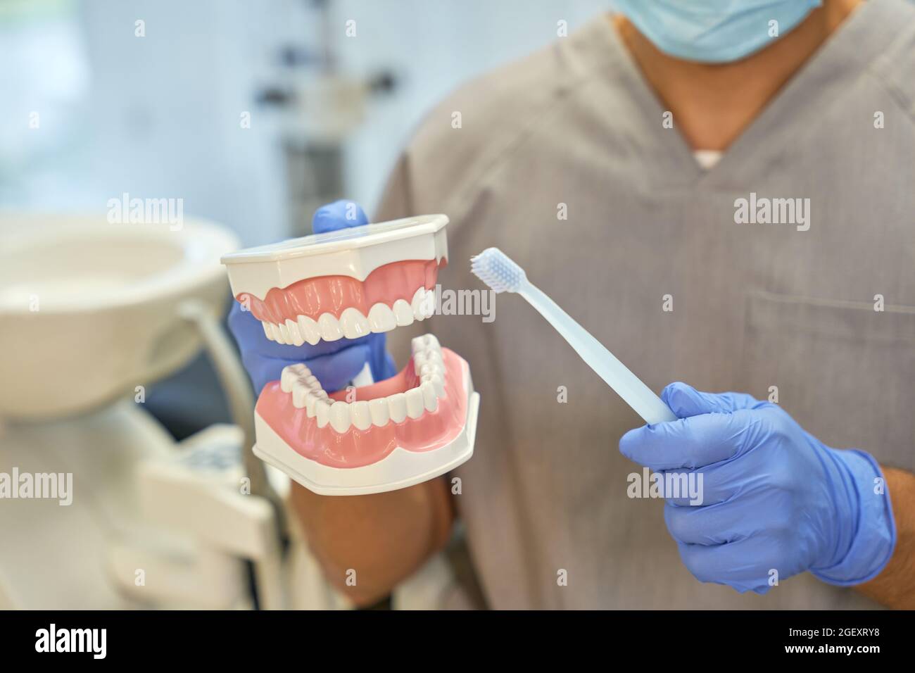 Dental specialist explaining teeth-brushing process with help of props ...
