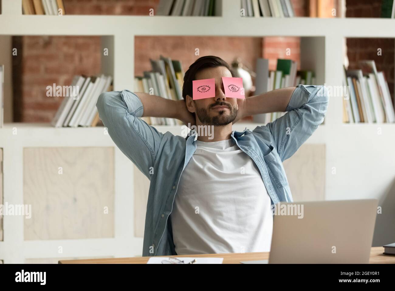 Employee relaxing at workplace with sticky notes on his eyes Stock ...