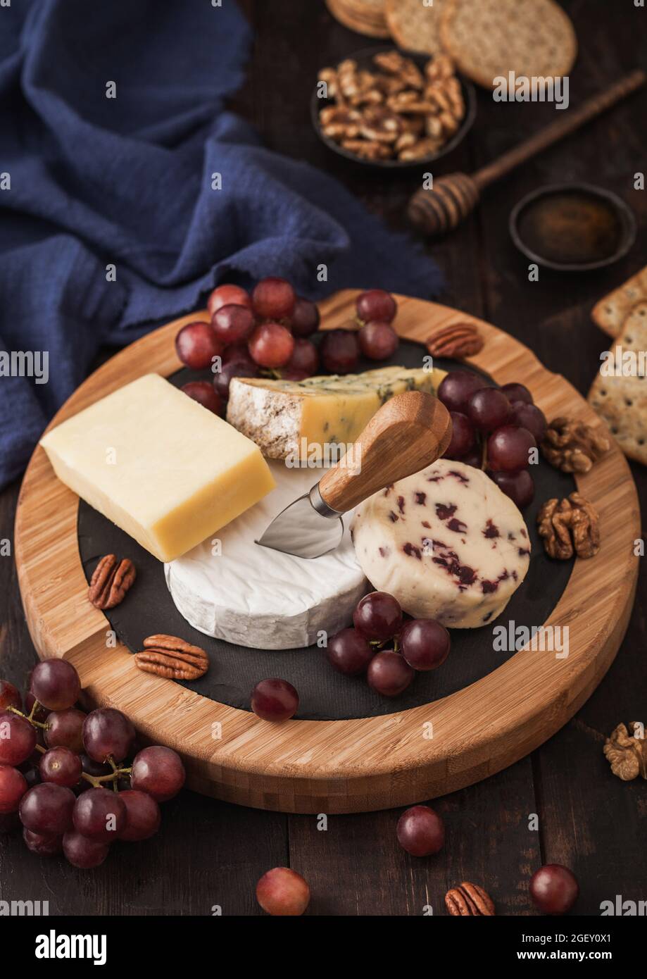 Selection of various cheese on the board and grapes on wooden table ...
