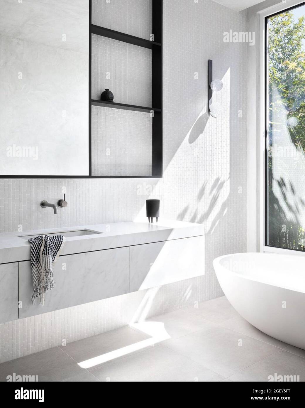 A vertical shot of an elegant white modern bathroom with a simple round ...