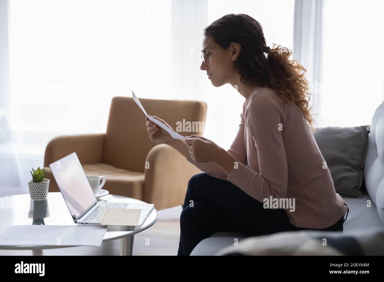 Serious woman reading letter looking concerned receive notification ...