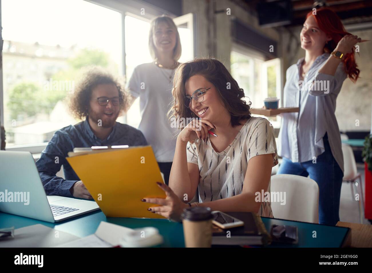 group of young people working together. female colleague showing folder ...