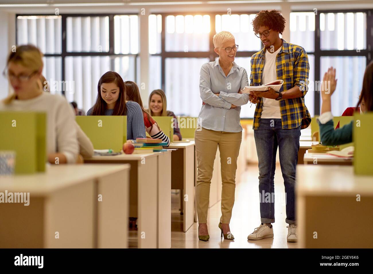 A male student in the university classroom talking to a professor ...