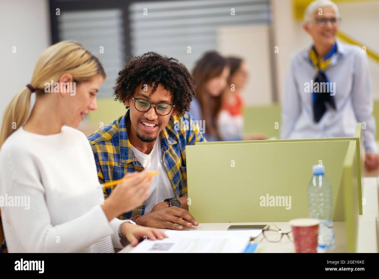 Colleagues helping each other about the lesson at the lecture in a ...