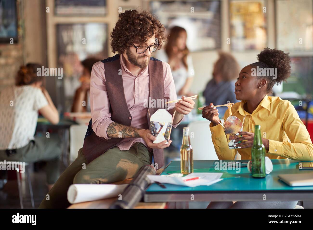 colleagues, multiethnic, male and female, having a break at work eating ...