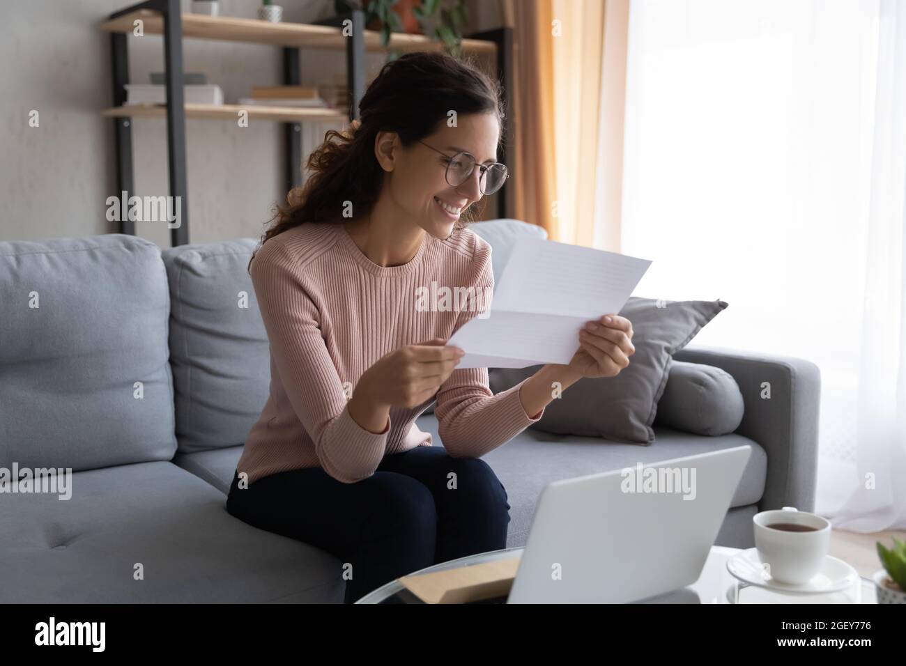 Lovely smiling woman sit on sofa reading letter Stock Photo - Alamy