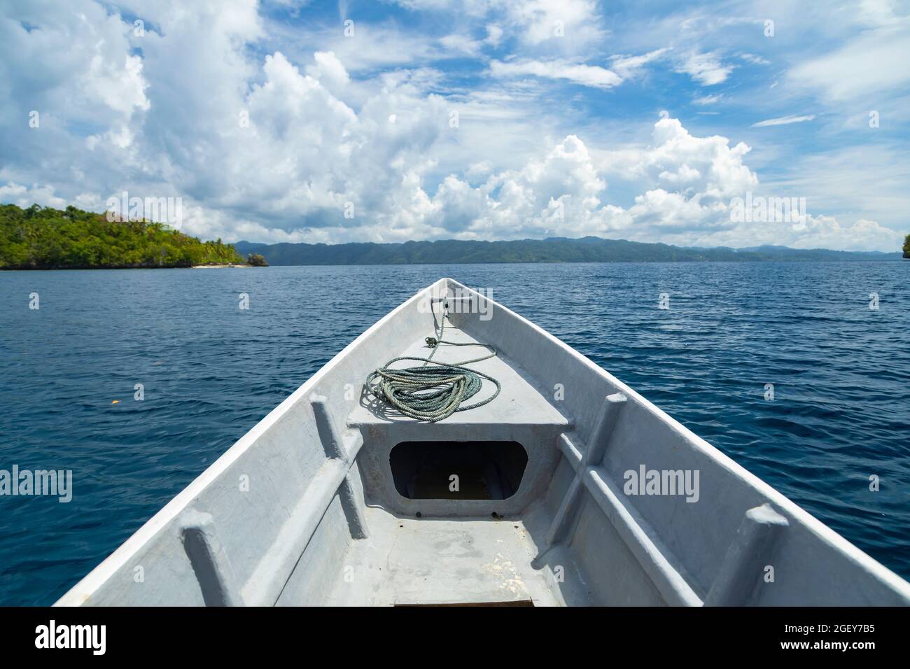 Bow of a motor boat plowing through the blue waters between the islands ...