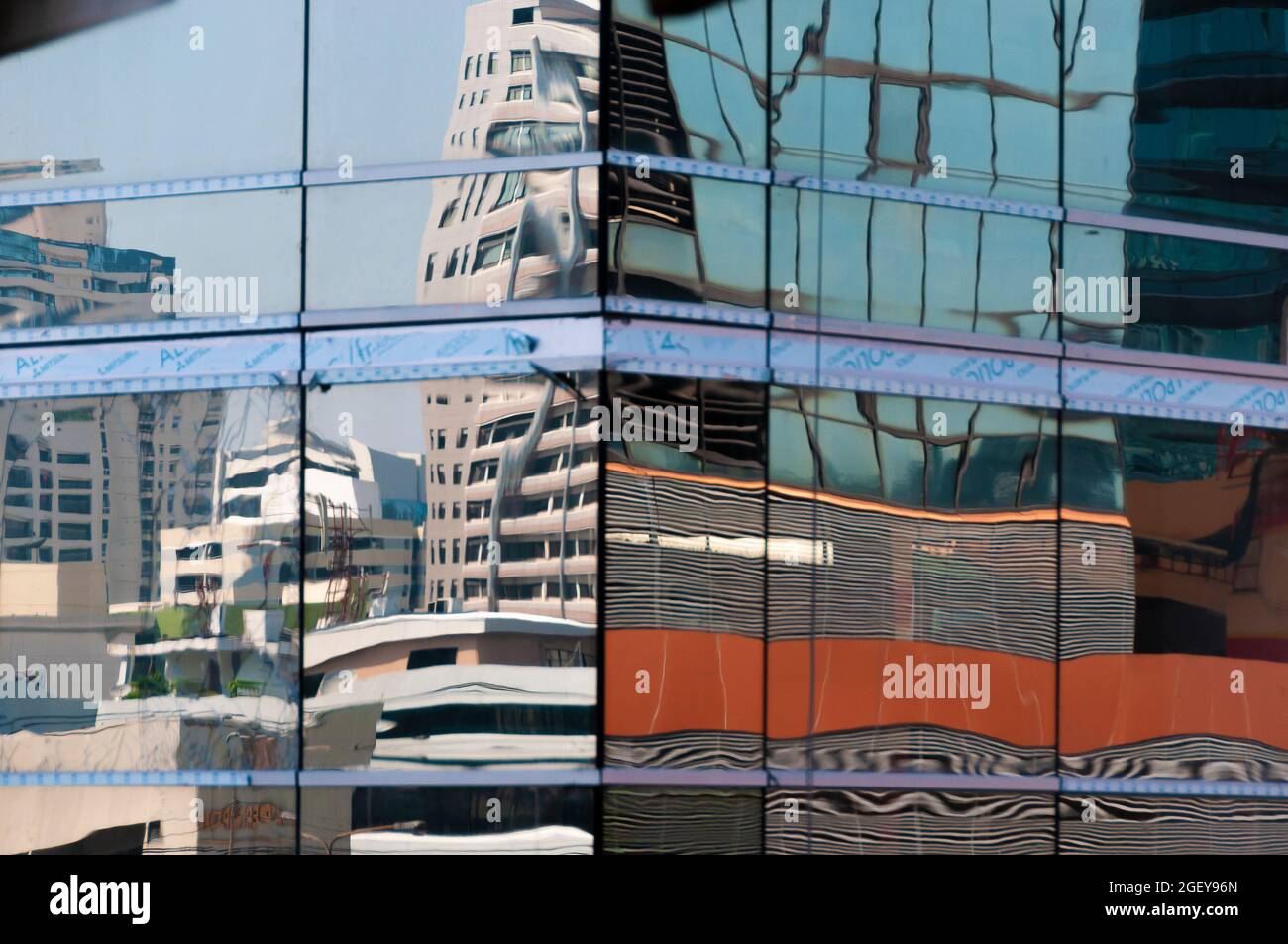 The distorted reflection of buildings seen in the glass facade of a ...