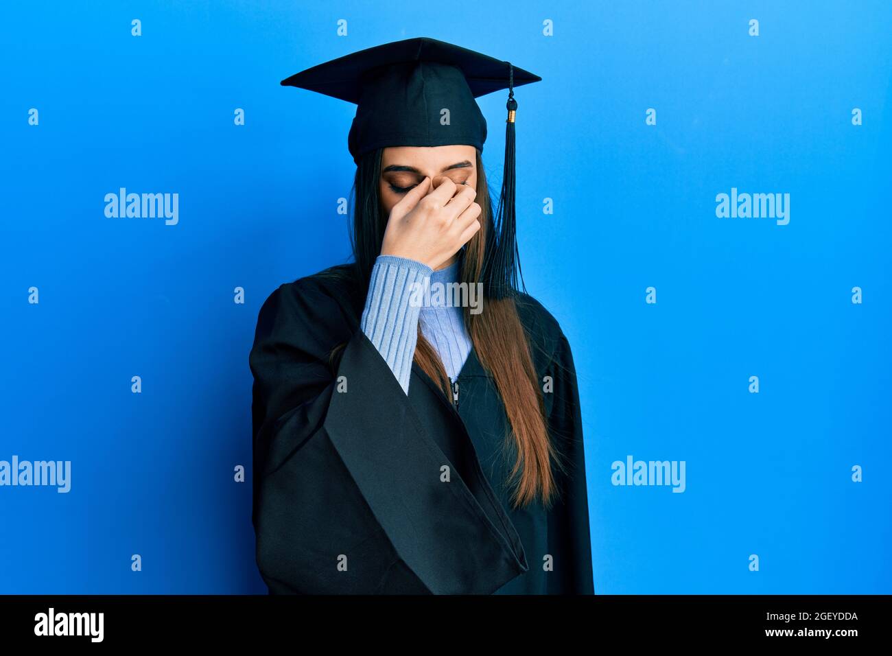 Beautiful brunette young woman wearing graduation cap and ceremony robe ...