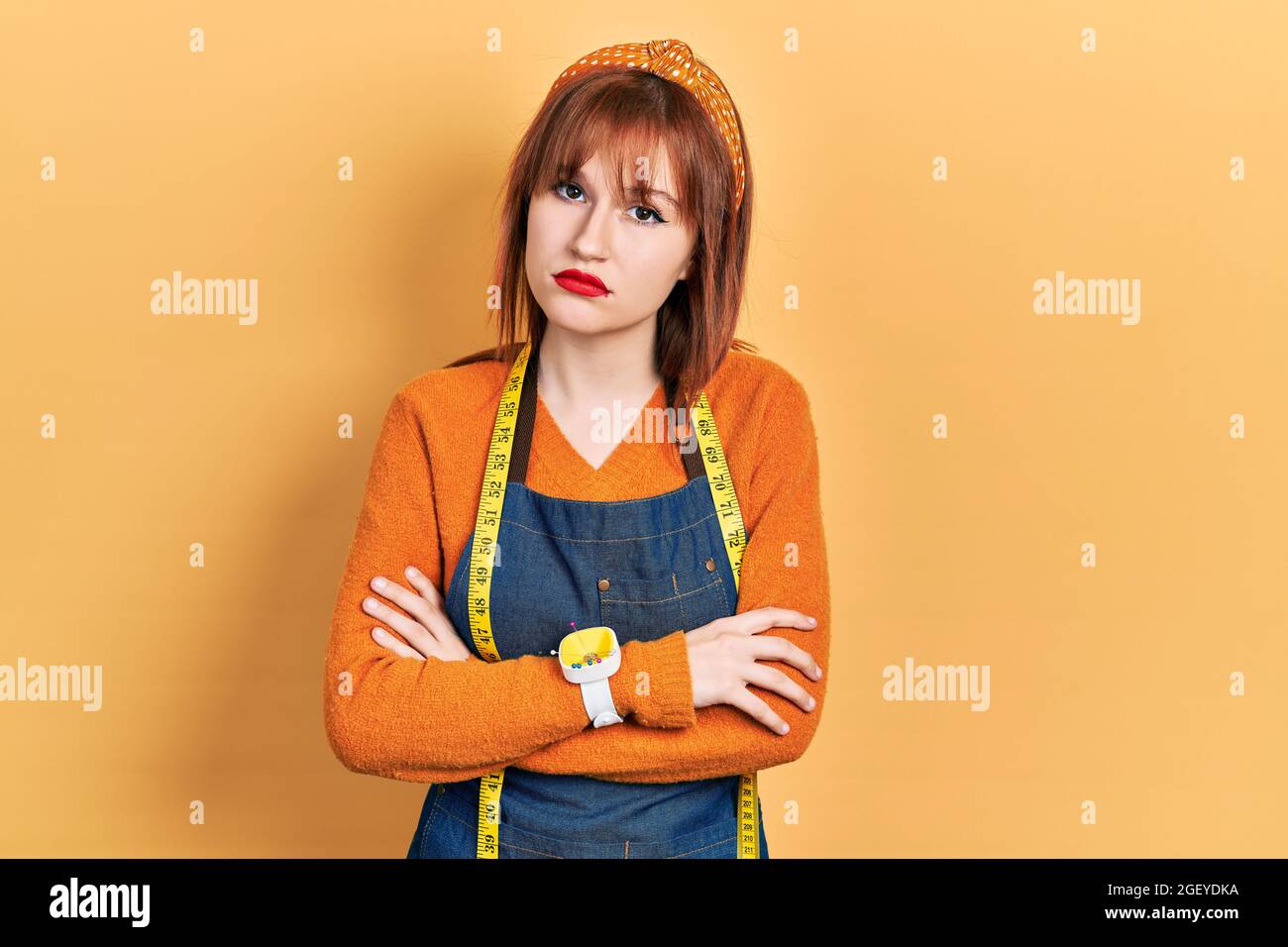 Redhead young woman dressmaker designer wearing atelier apron depressed ...