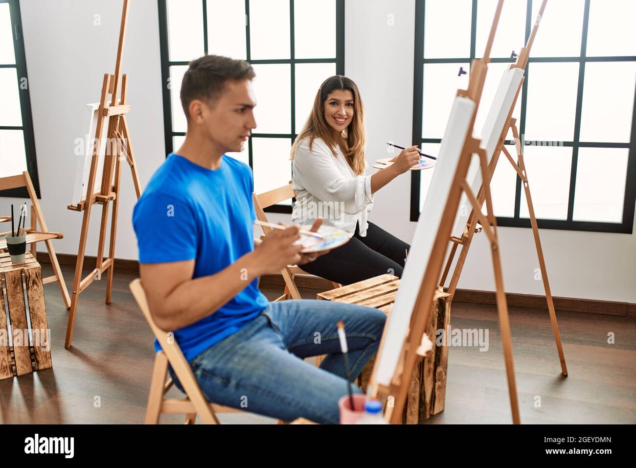 Two students smiling happy painting at art school Stock Photo - Alamy