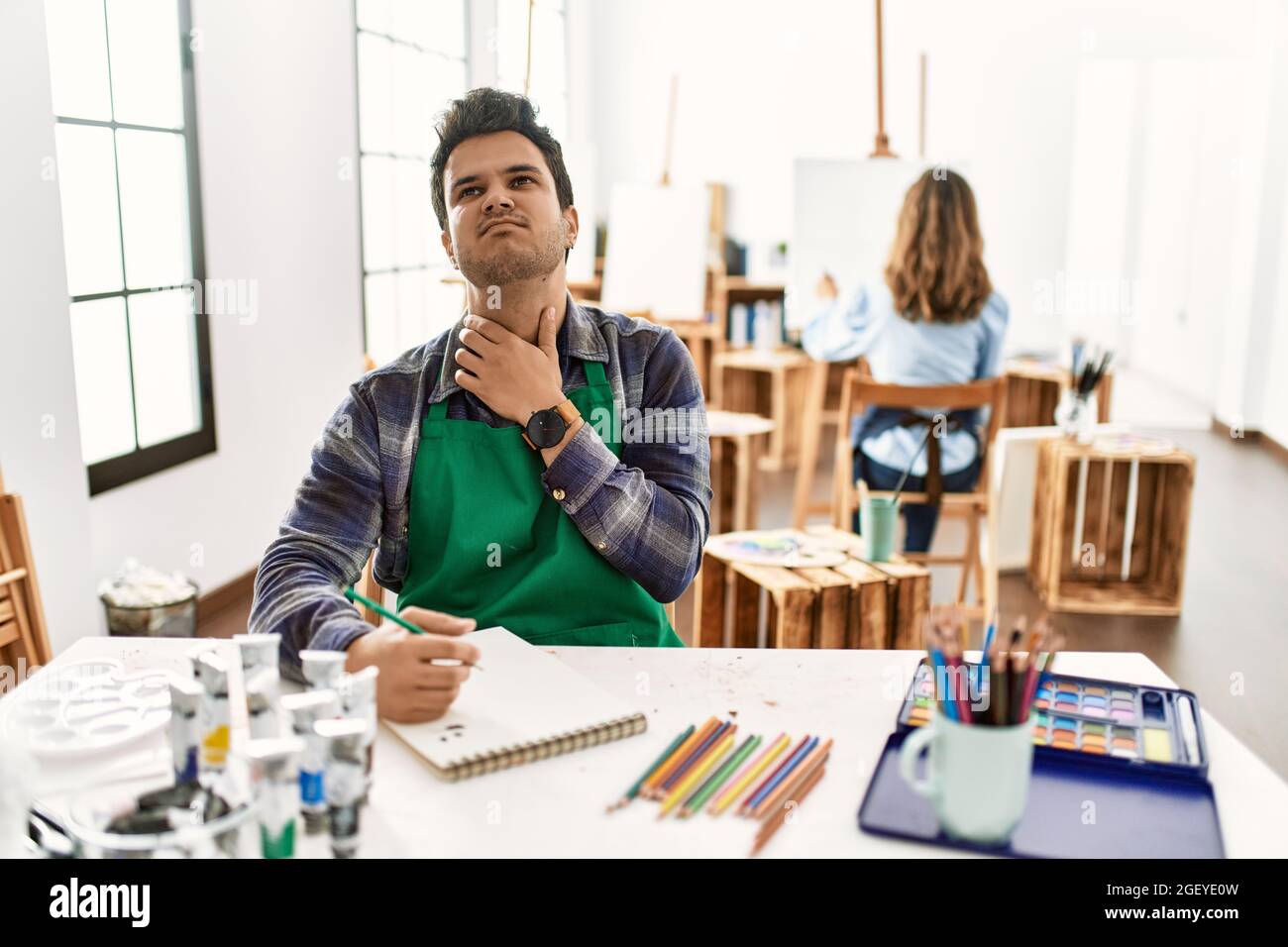 Young artist man at art studio touching painful neck, sore throat for ...