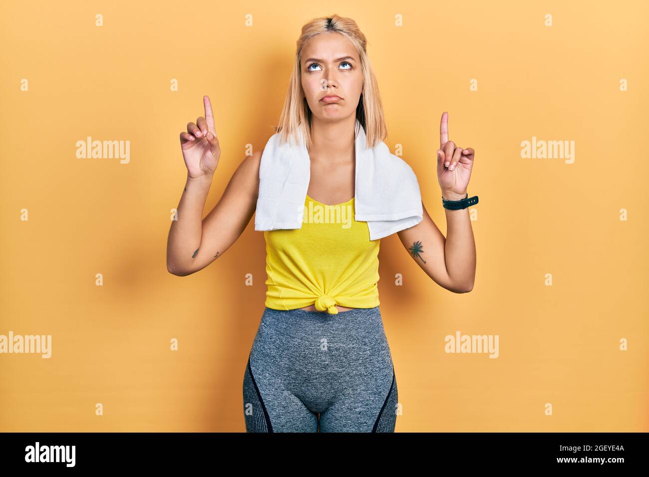 Beautiful blonde sports woman wearing workout outfit pointing up ...
