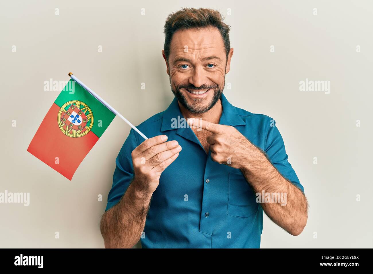 Middle age man holding portugal flag smiling happy pointing with hand ...