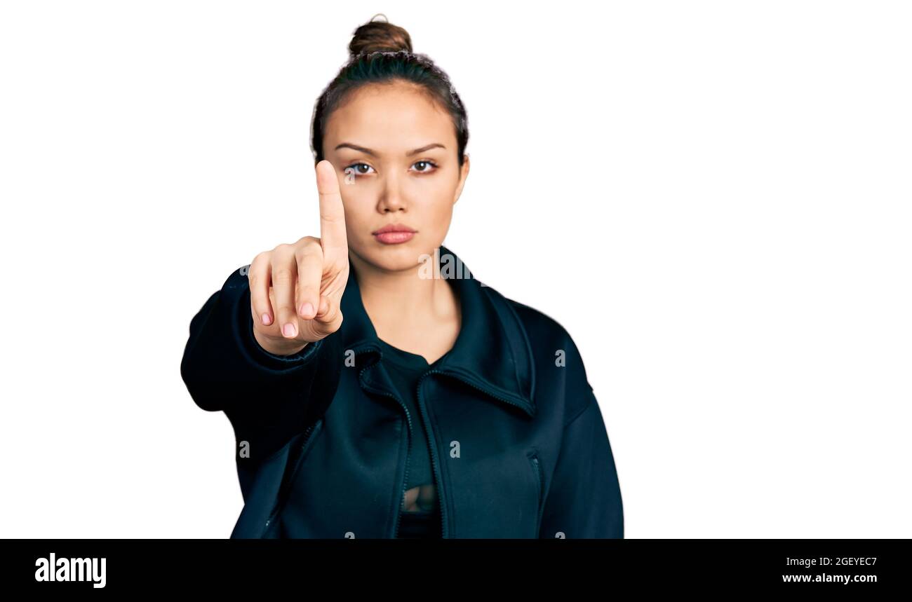 Young hispanic girl wearing sportswear pointing with finger up and ...