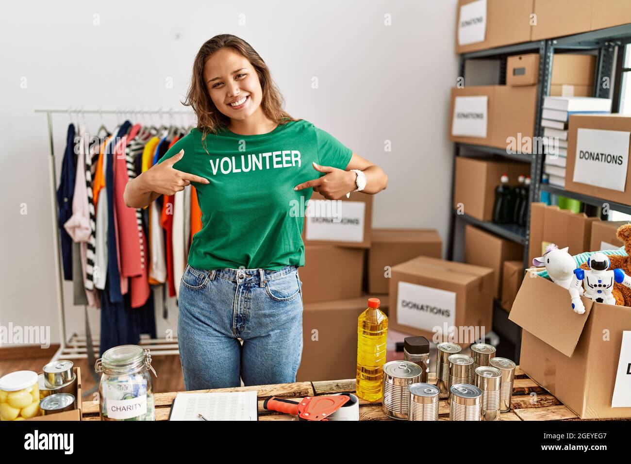 Beautiful hispanic woman wearing volunteer t shirt at donations stand ...