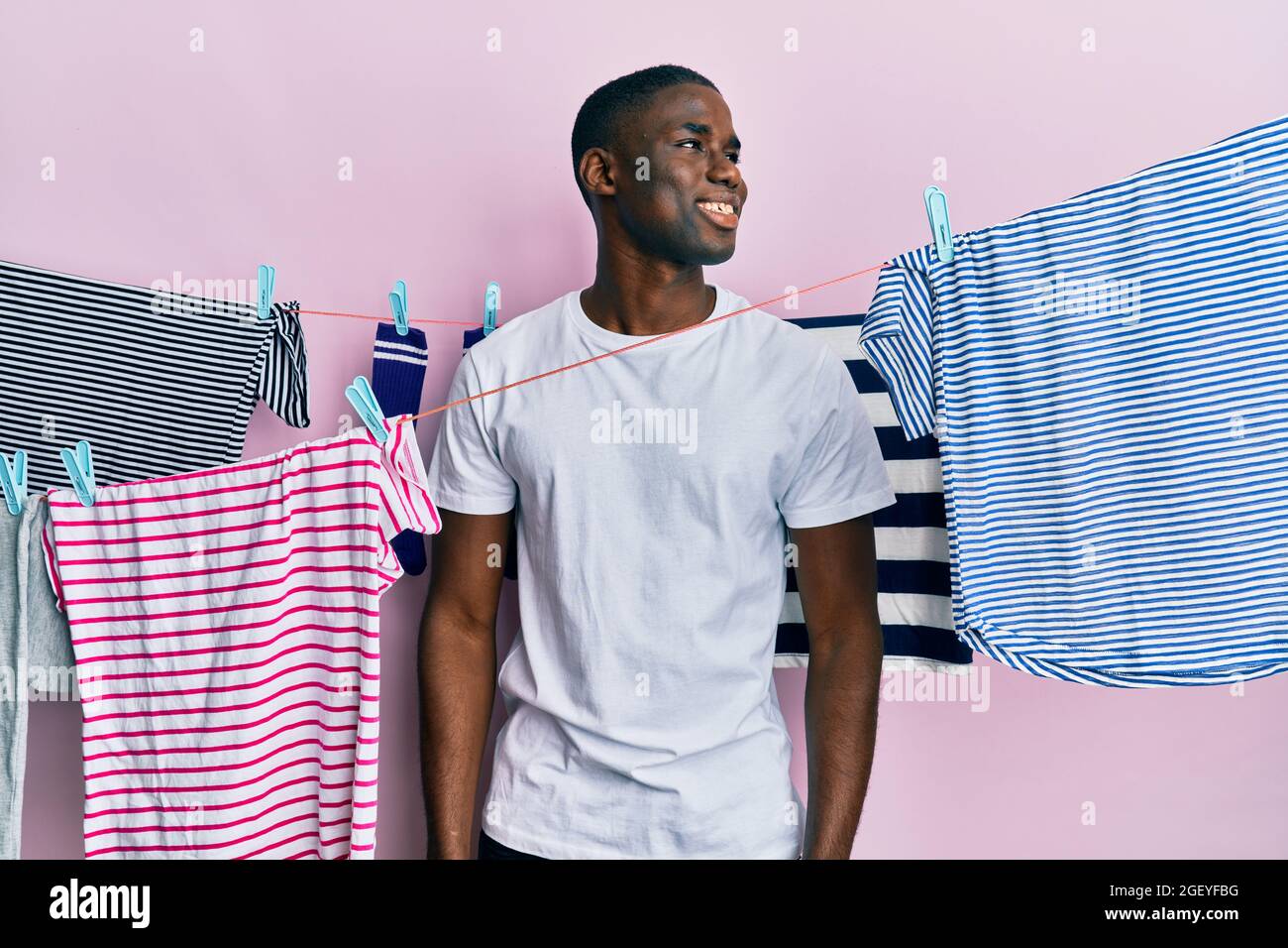 Young african american man washing clothes at clothesline looking to ...