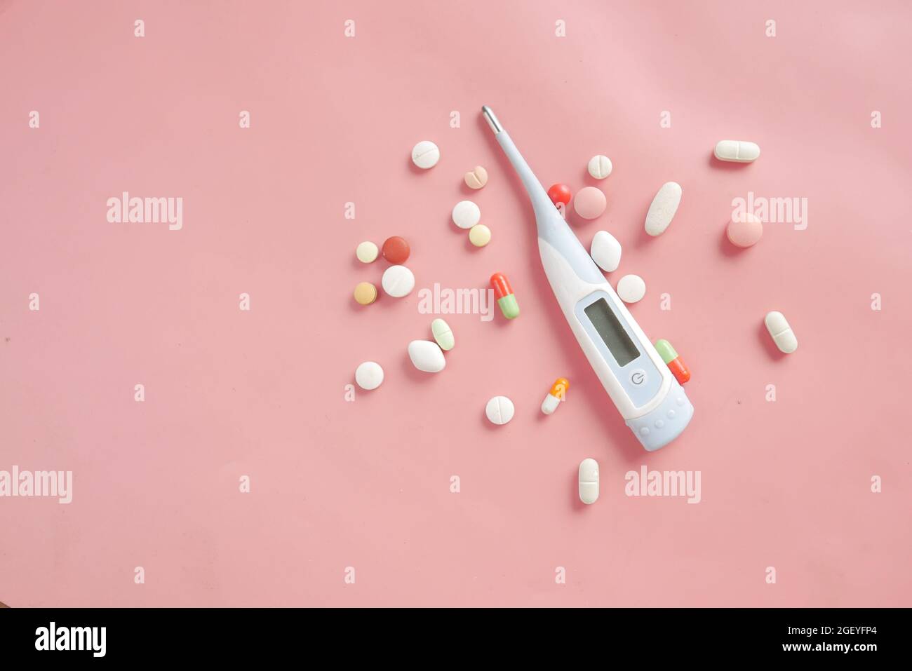 digital thermometer and pills pink background Stock Photo - Alamy